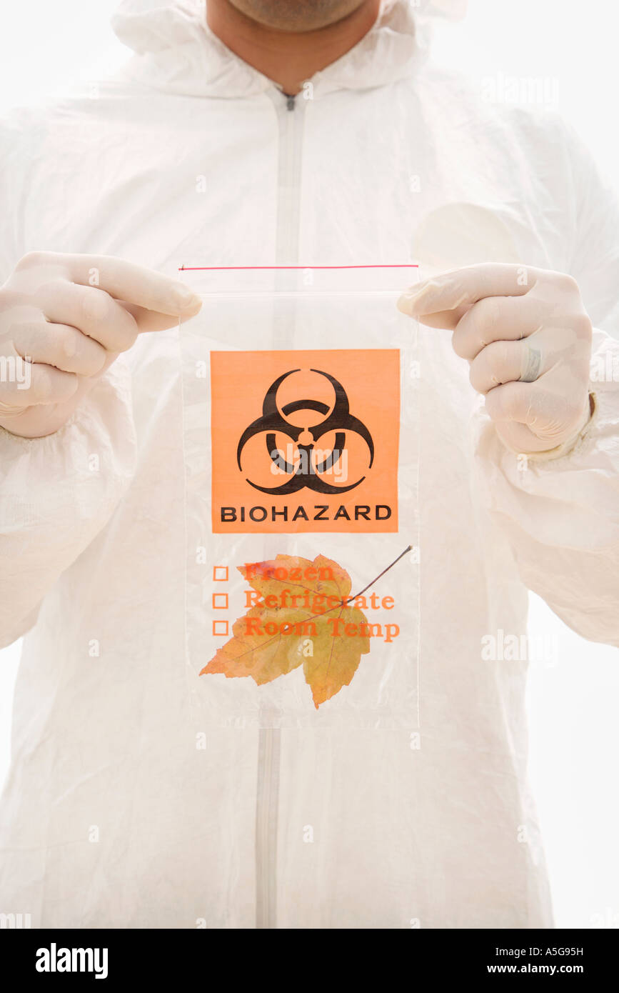 Man in biohazard suit and rubber gloves holding plastic biohazard bag ...