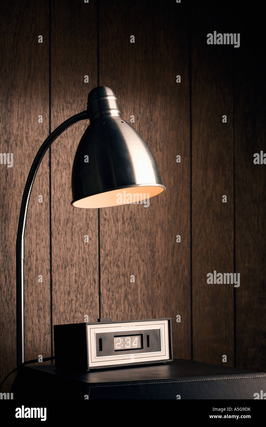 Desk lamp shining down on retro clock against wood paneling Stock Photo ...
