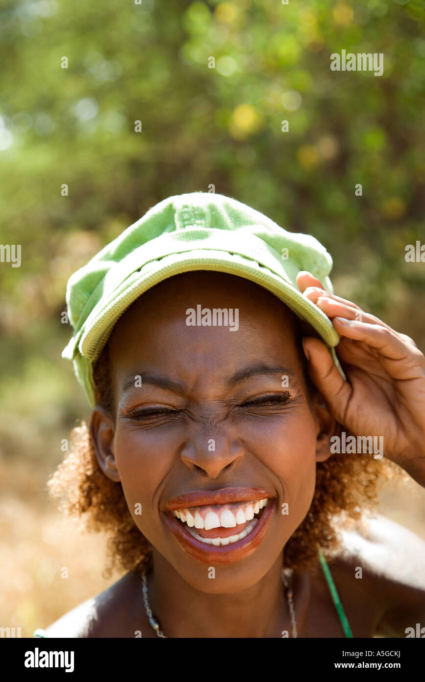 MId adult Black female smiling with hand on cap and squinted eyes Stock ...
