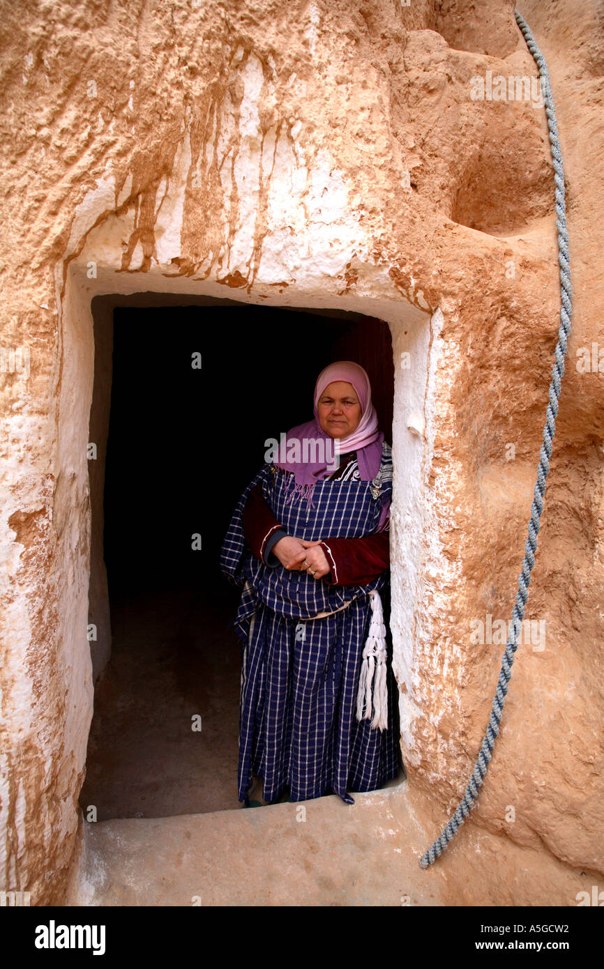 Vertical portrait of troglodyte woman in the doorway of her cave home ...