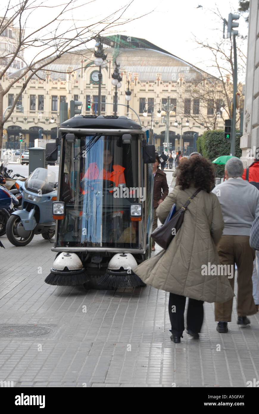 A street cleaning machine being driven along a wide pavement near the ...