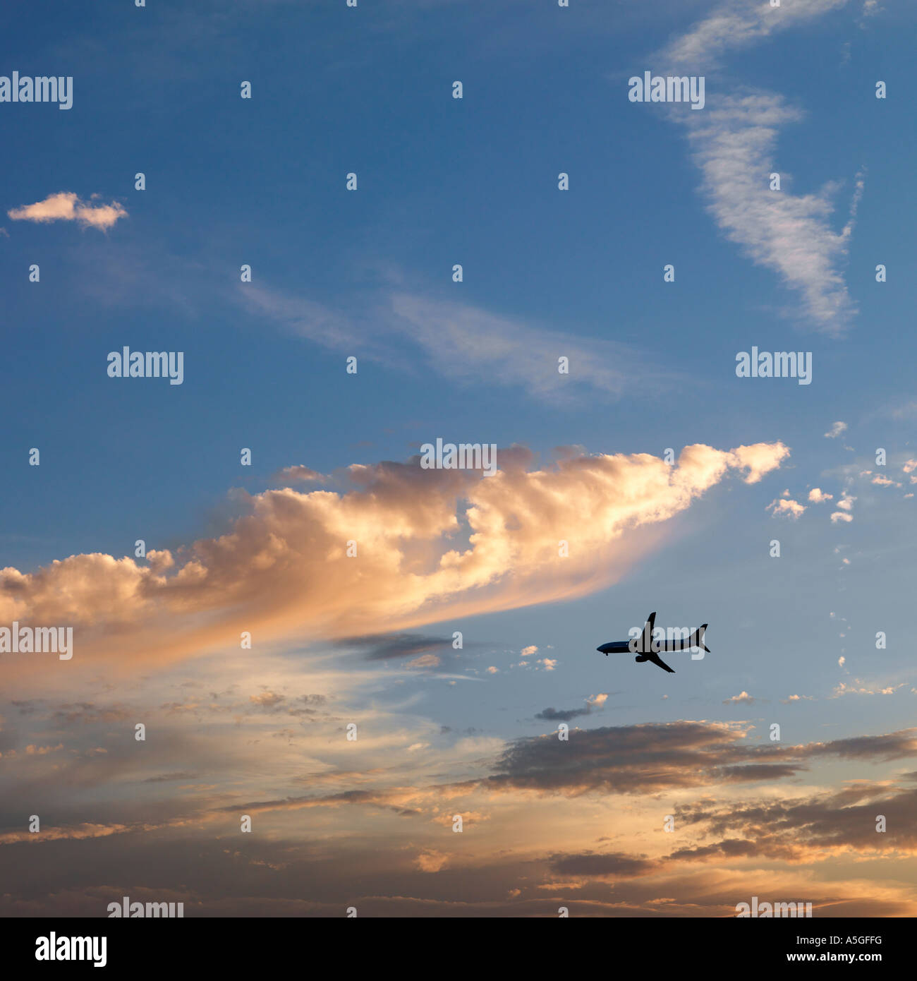 Airplane jetting across colored sky Stock Photo - Alamy