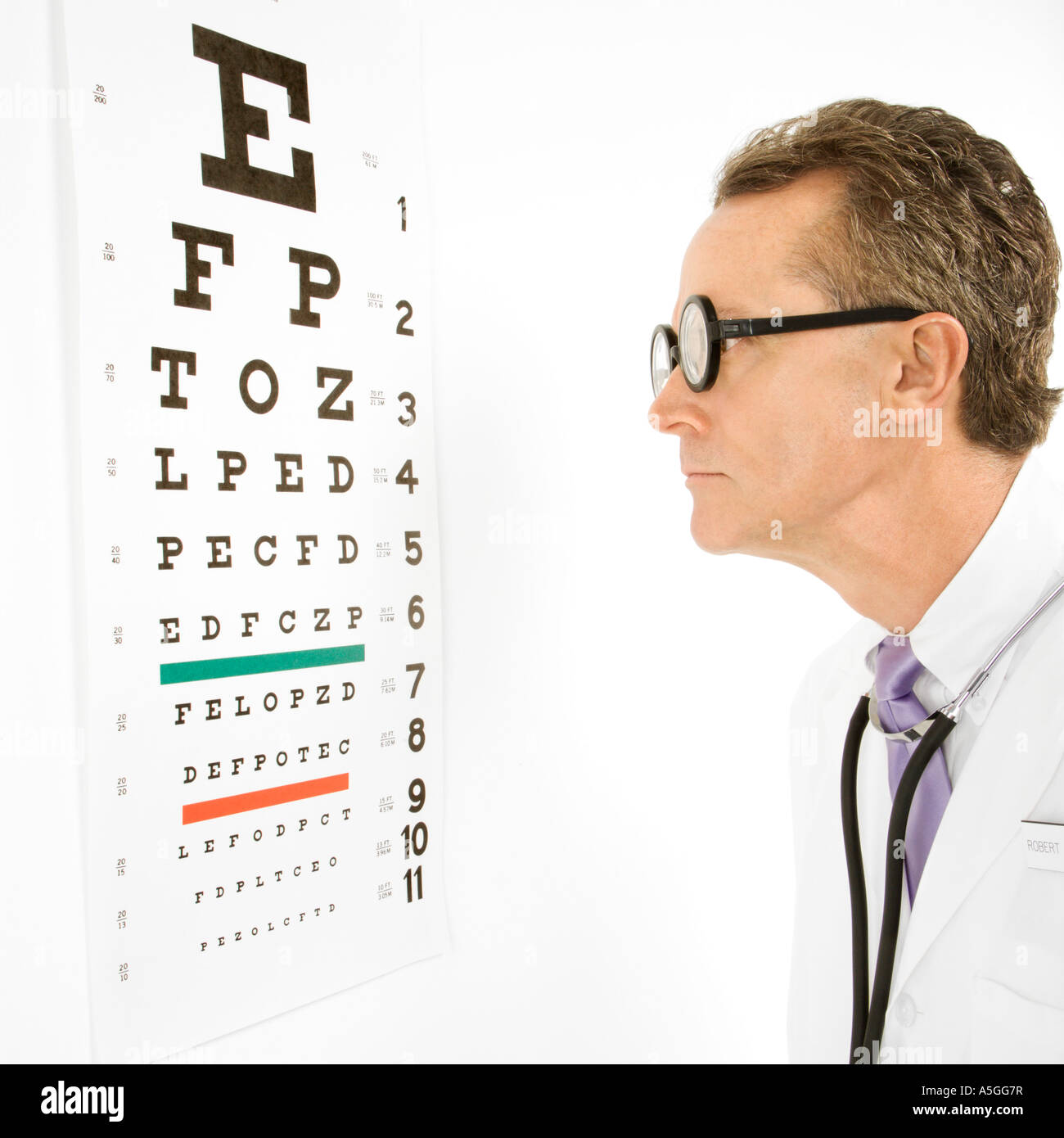 Mid adult Caucasian male doctor wearing eyeglasses looking at an eye ...