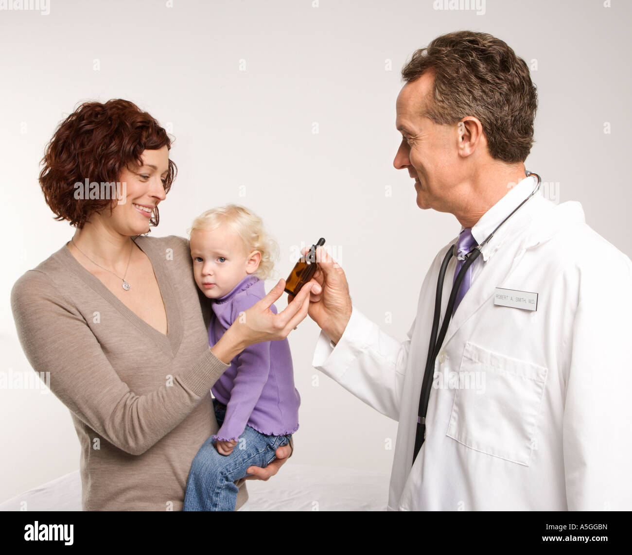 Middle aged adult Caucasian male doctor handing Caucasian mother ...