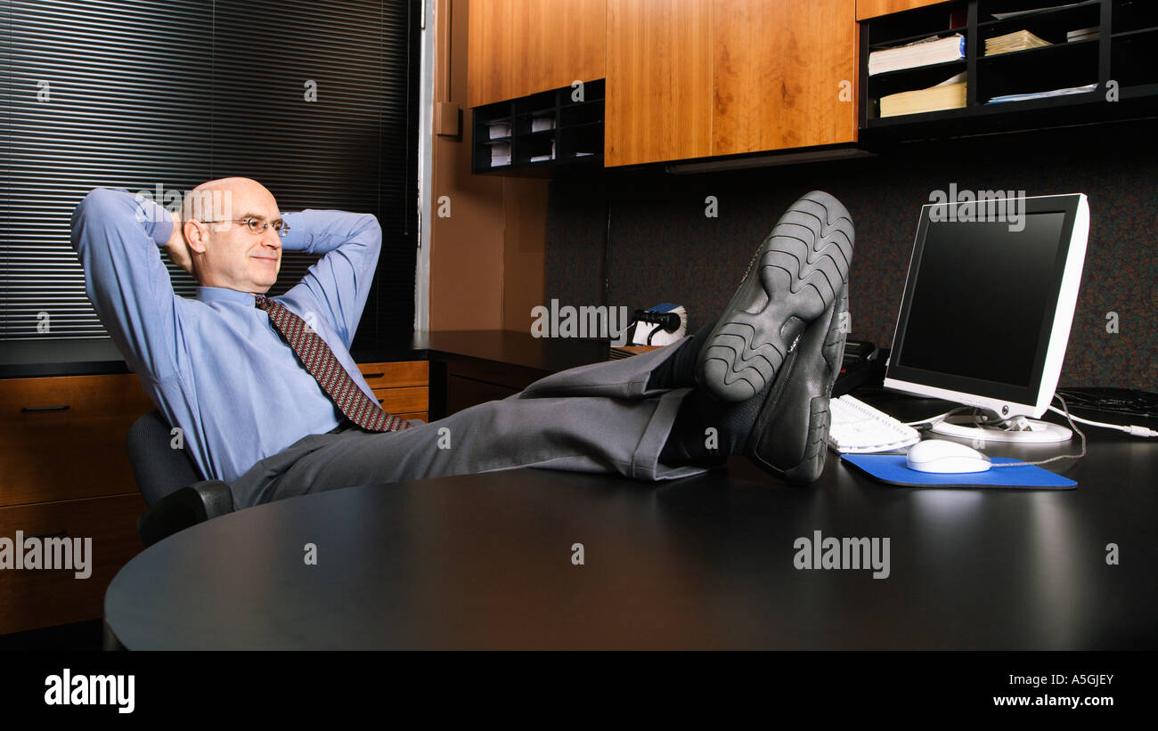 Caucasian middle aged businessman in office sitting with feet on desk Stock Photo - Alamy