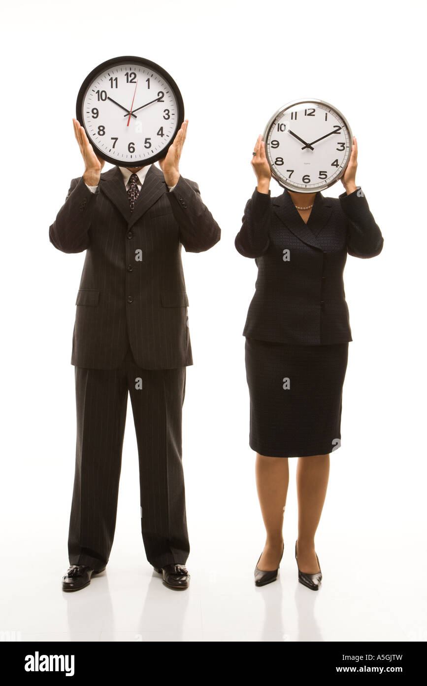 Businessman and businesswoman holding clocks in over faces Stock Photo ...