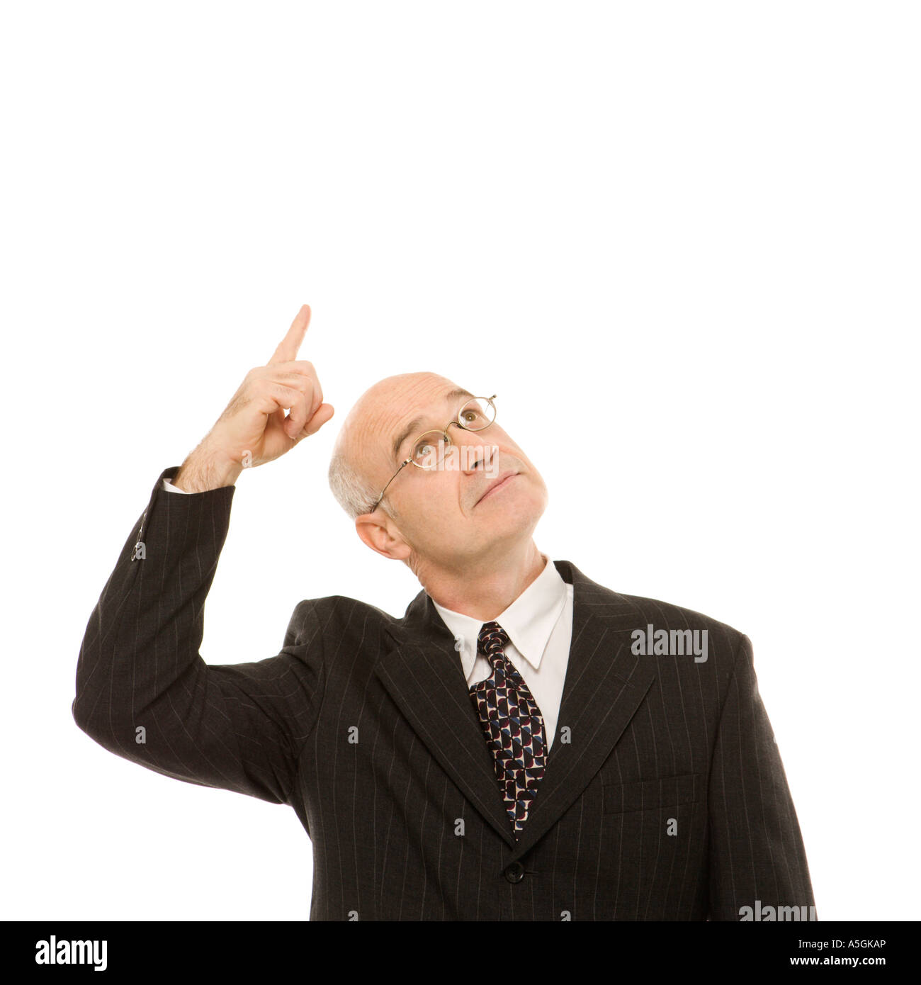 Businessman looking and pointing up standing against white background ...