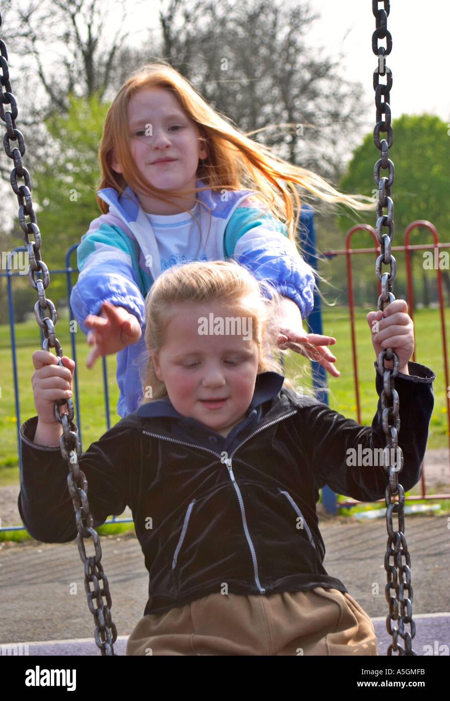 Sisters playing on a park swing Stock Photo - Alamy