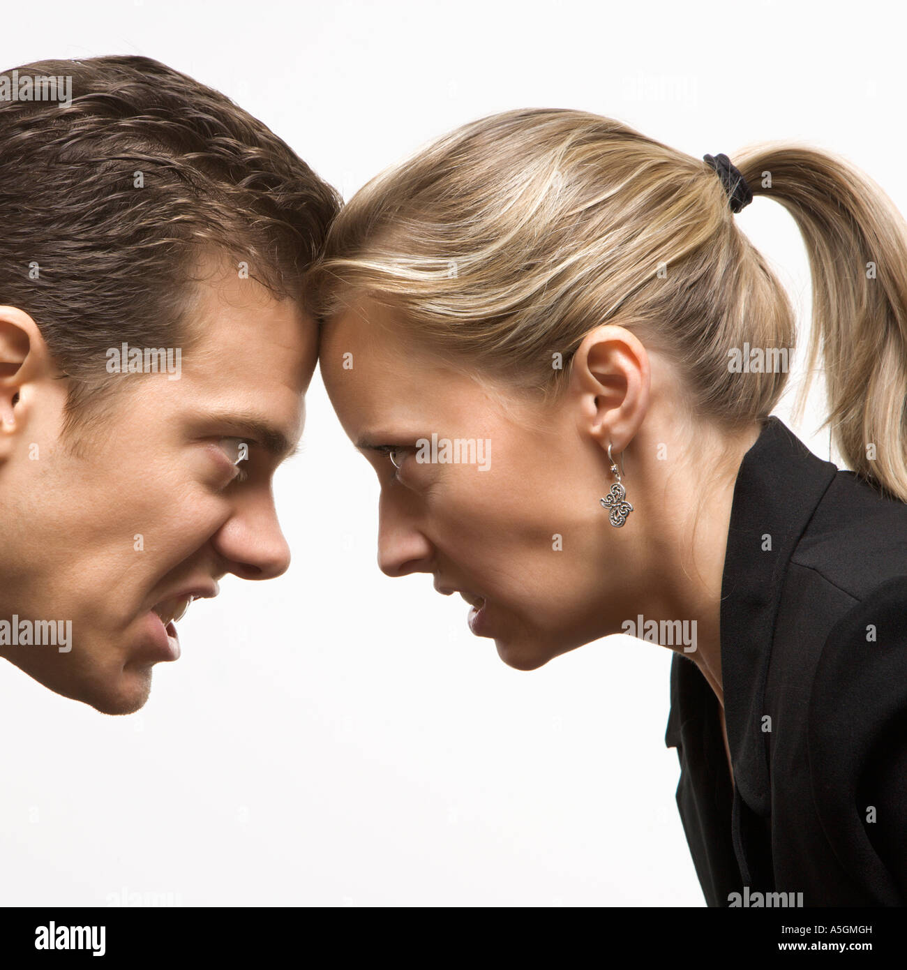 Caucasian mid adult man and woman with foreheads together staring at ...
