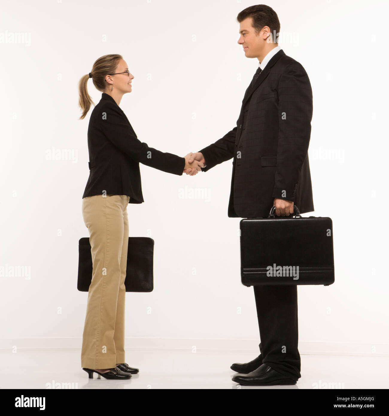 Caucasian mid adult businessman and woman shaking hands and holding briefcases Stock Photo - Alamy