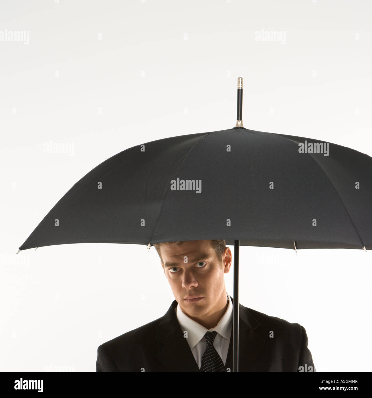 Caucasian mid adult businessman looking out at viewer from under ...