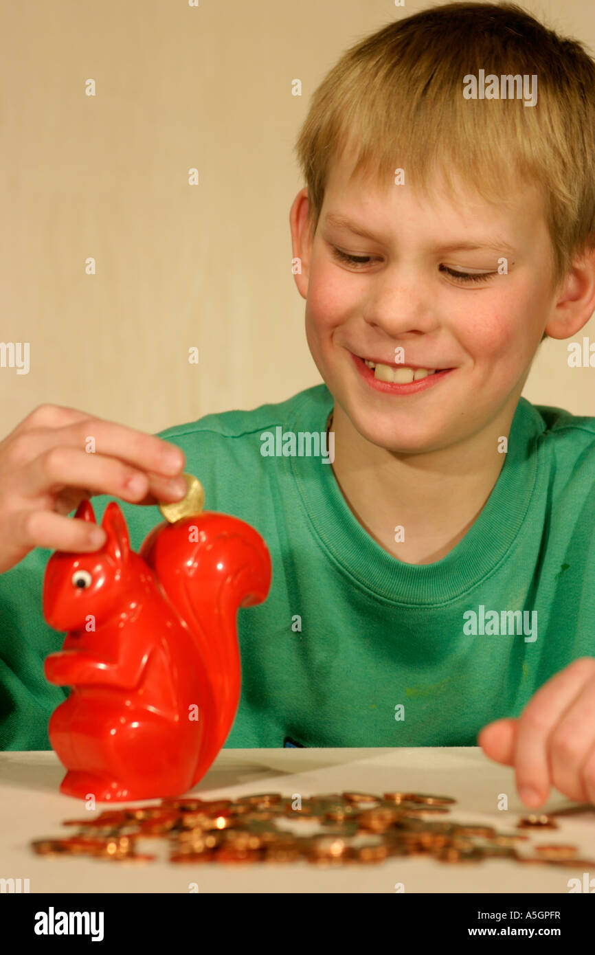 portrait of a happy little boy putting money into his savings box Stock ...