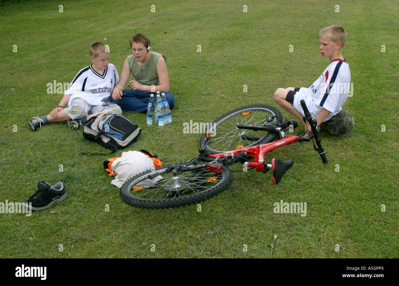 three young boys having a break on a football field Stock Photo - Alamy