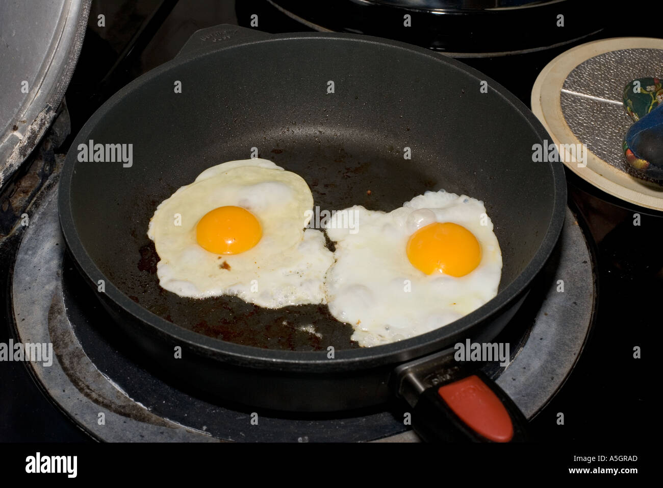Two eggs frying in large black teflon pan Cotswolds UK Stock Photo - Alamy