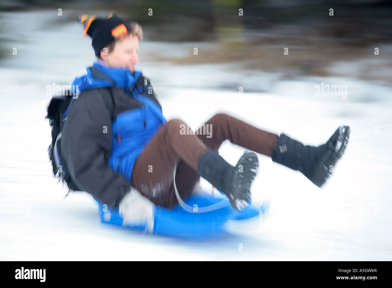 Young woman sledding on a sled by a toboggan run. Torfhaus resort in ...