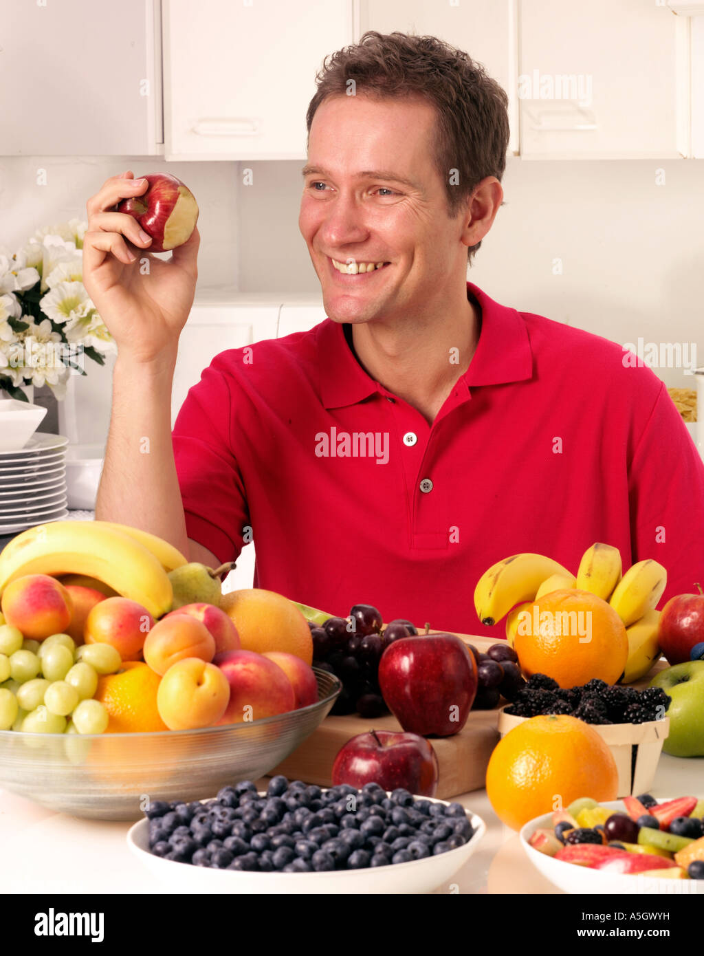 MAN IN KITCHEN WITH FRUIT EATING APPLE Stock Photo - Alamy