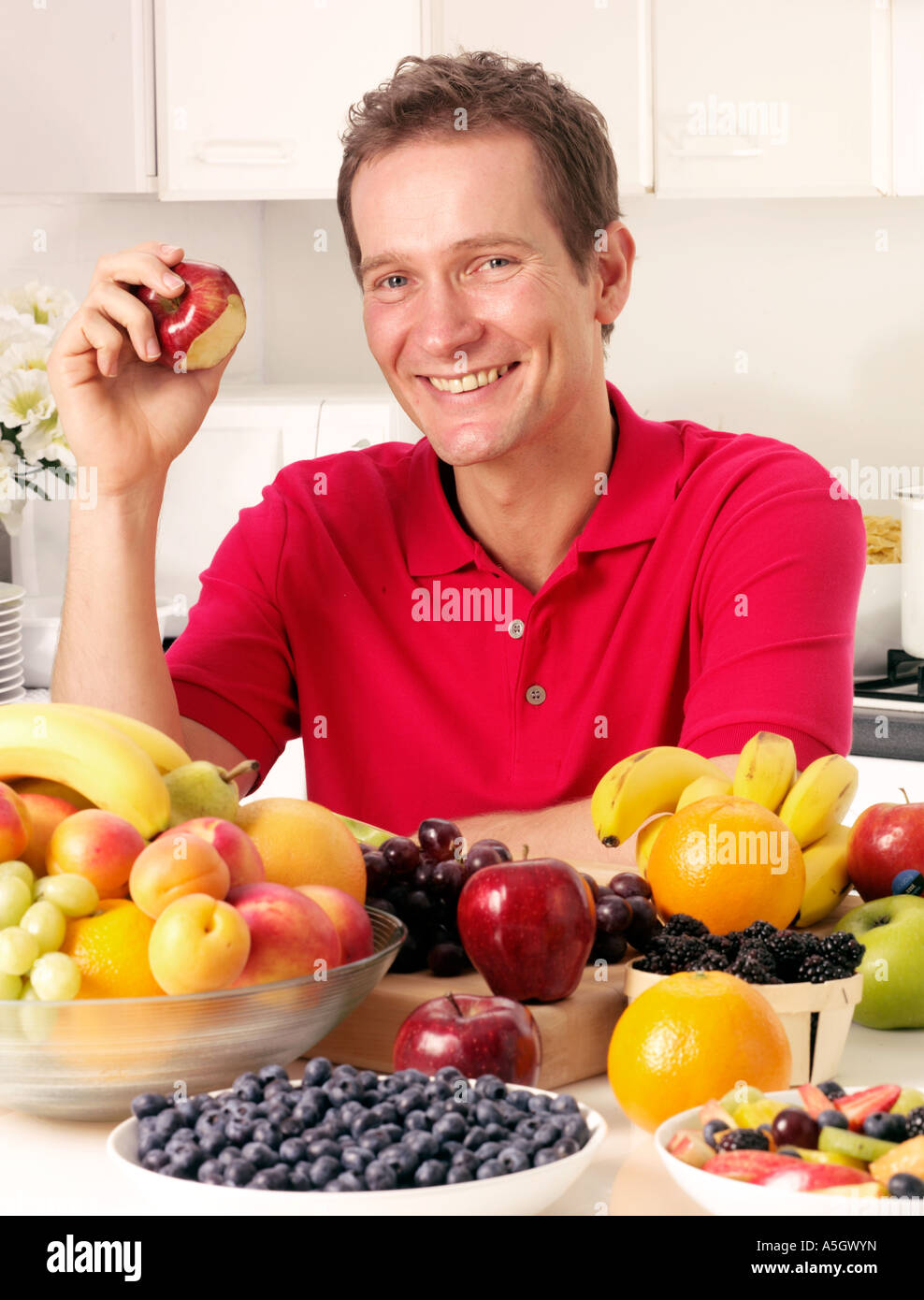 MAN IN KITCHEN WITH FRUIT EATING APPLE Stock Photo - Alamy