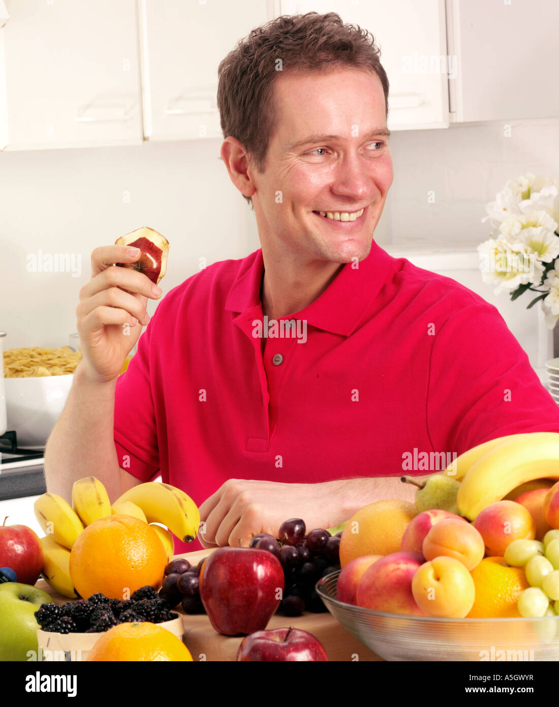MAN IN KITCHEN WITH FRUIT EATING APPLE Stock Photo - Alamy