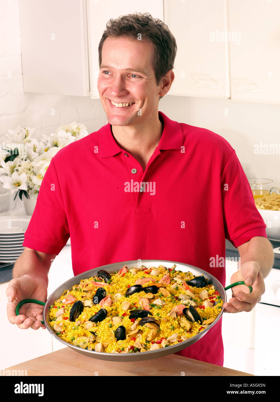 MAN IN KITCHEN WITH SPANISH PAELLA Stock Photo - Alamy