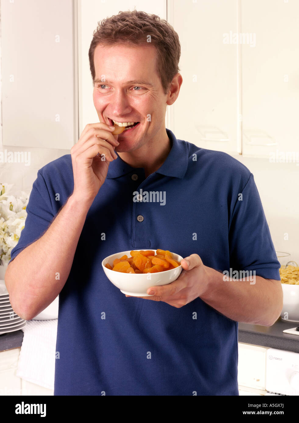 MAN IN KITCHEN EATING DRIED APRICOTS Stock Photo - Alamy