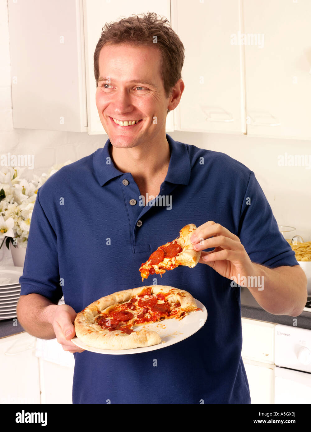 MAN IN KITCHEN EATING PIZZA Stock Photo - Alamy