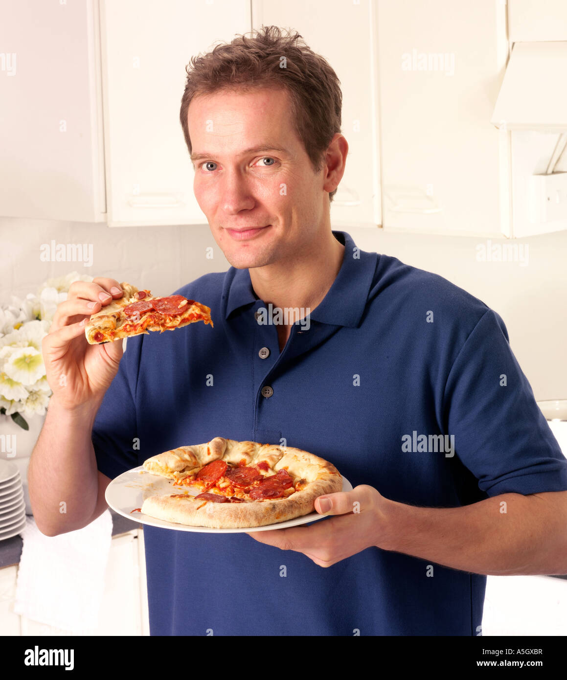 MAN IN KITCHEN EATING PIZZA Stock Photo - Alamy