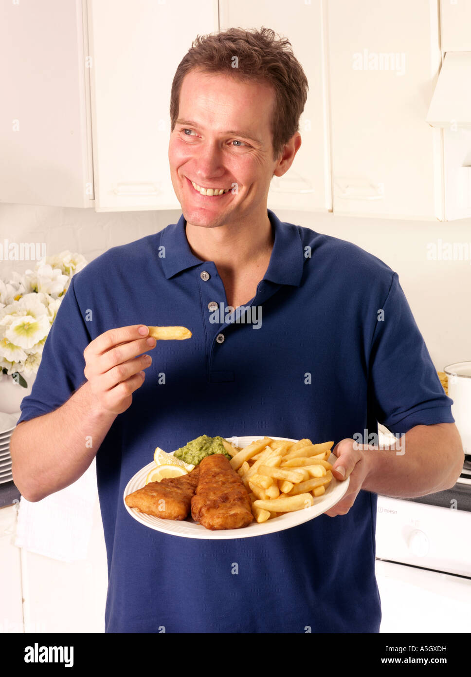 MAN IN KITCHEN EATING FISHING AND CHIPS Stock Photo - Alamy