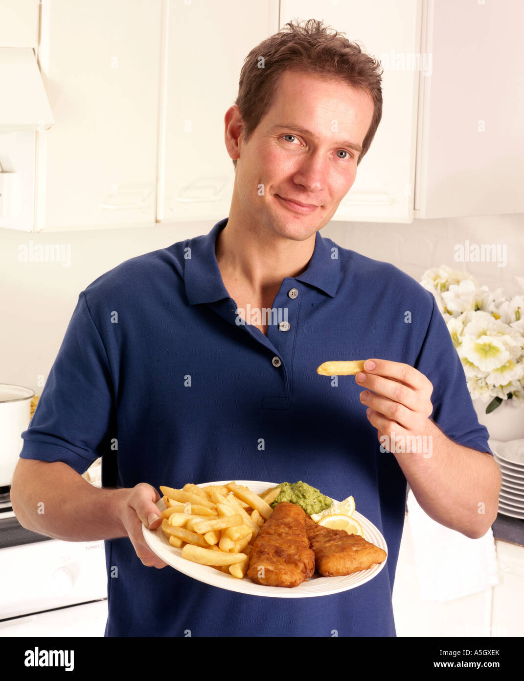 MAN IN KITCHEN EATING FISHING AND CHIPS Stock Photo - Alamy