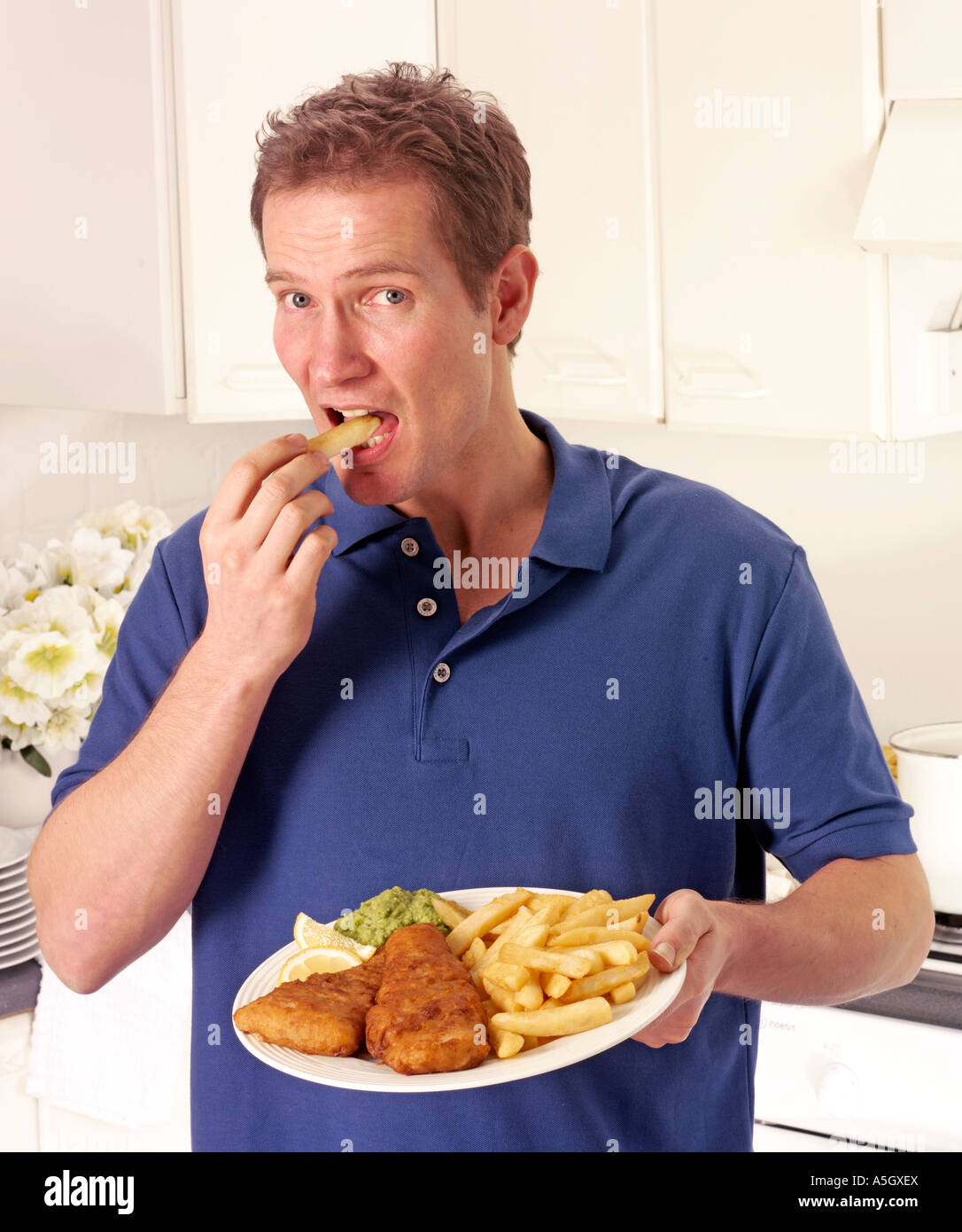 MAN IN KITCHEN EATING FISHING AND CHIPS Stock Photo - Alamy