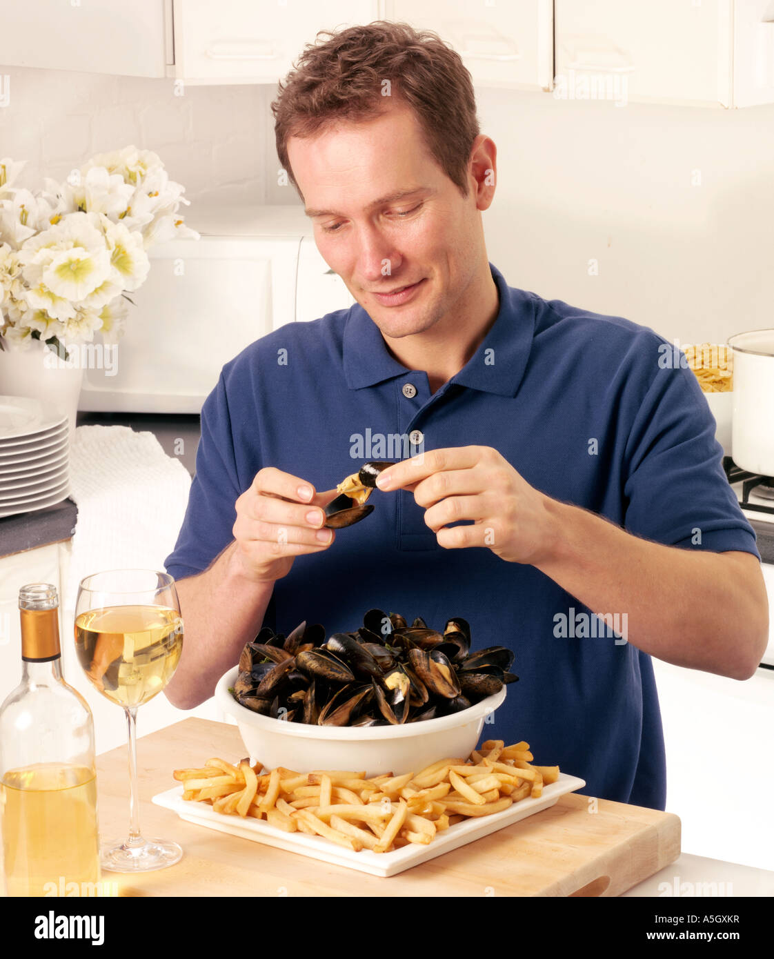 MAN EATING MUSSELS AND FRENCH FRIES OR MOULES FRITES Stock Photo - Alamy