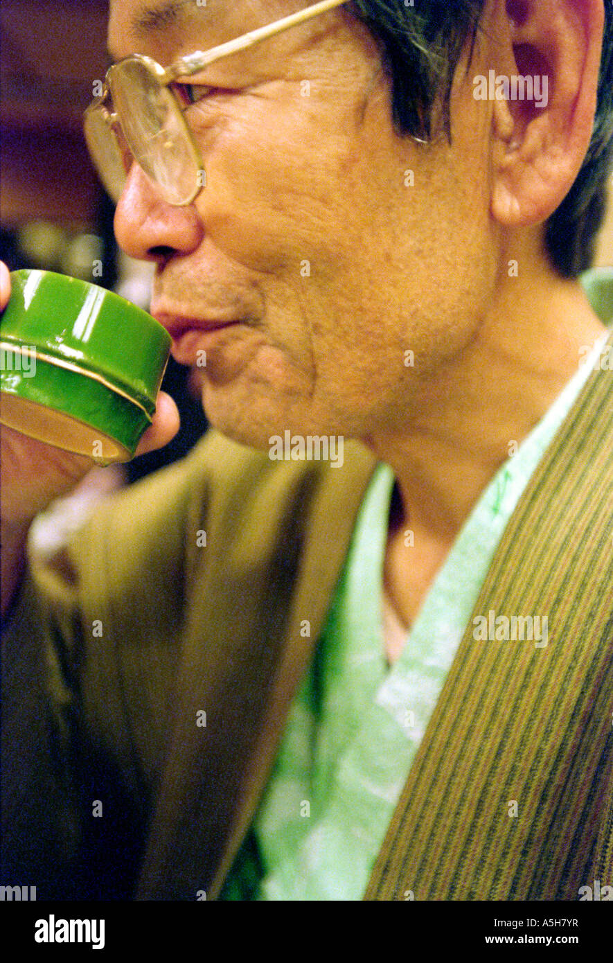 Man in traditional dress drinking Sake from an earthenwear cup. Banquet ...