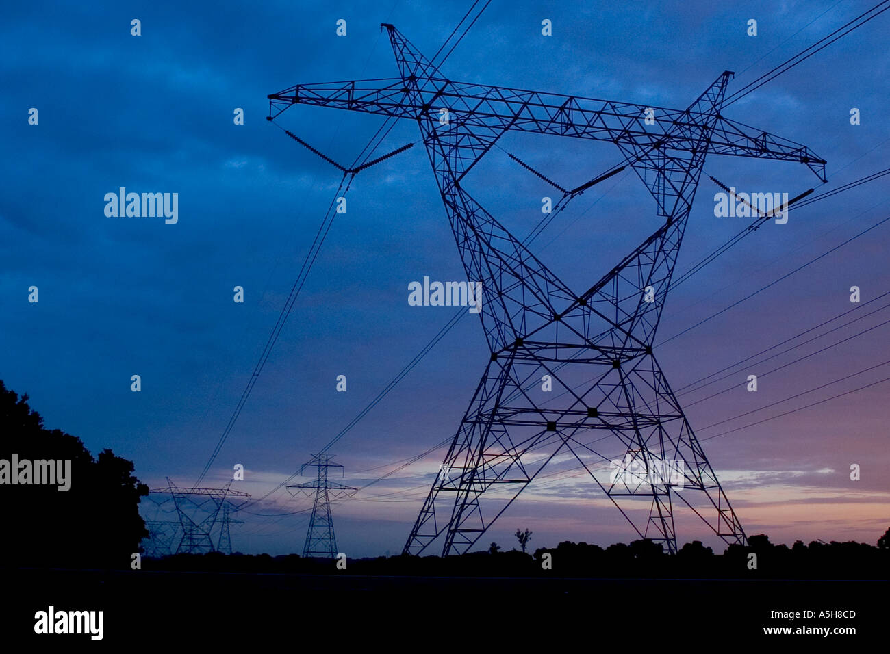 Electric utility tower silhouetted against a bright sunrise Stock Photo ...