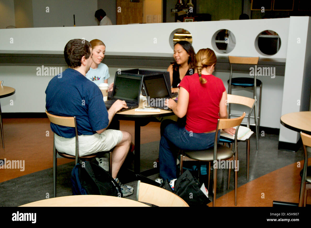 Four college students at table studying with laptop computers Stock ...