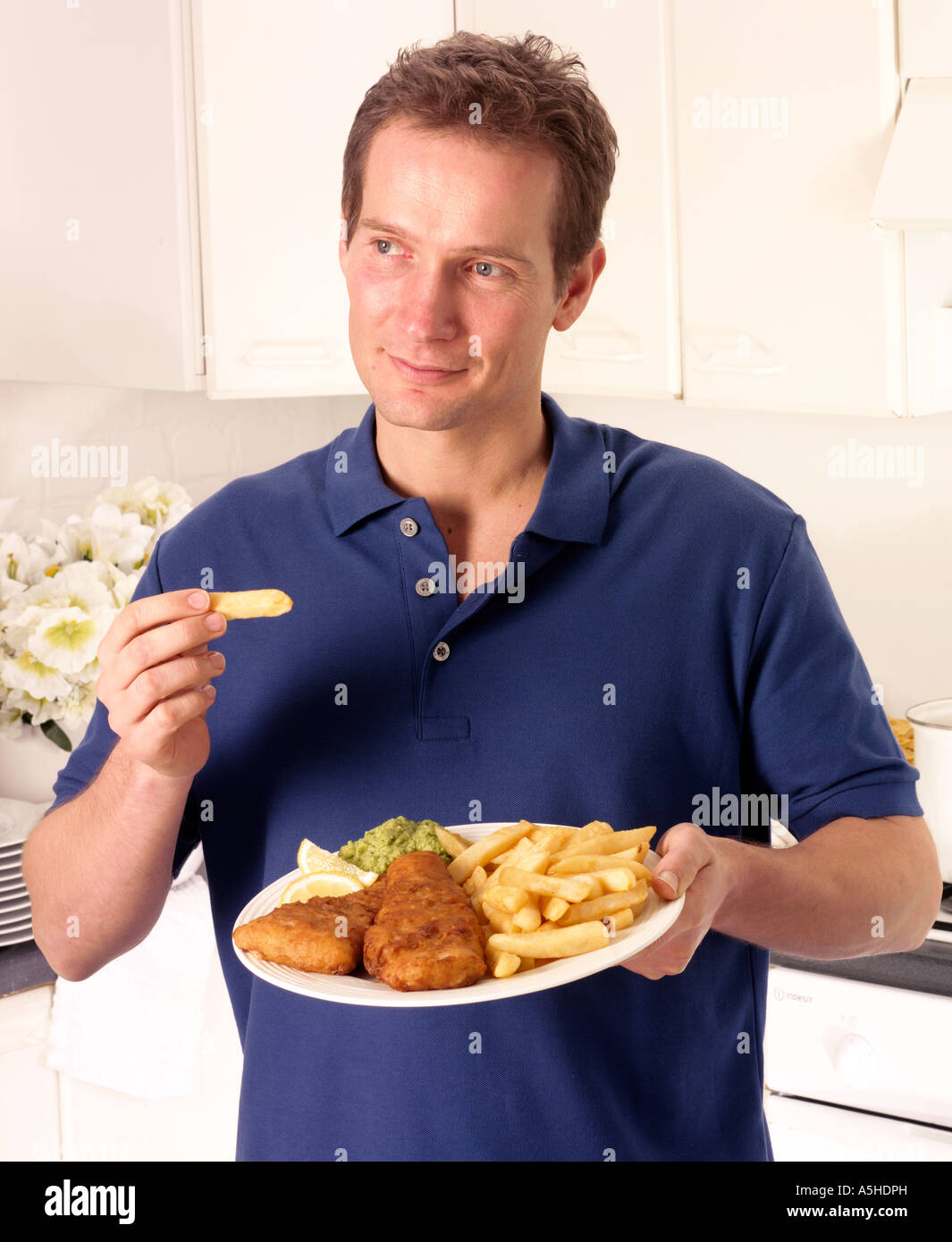 MAN IN KITCHEN EATING FISH AND CHIPS Stock Photo - Alamy