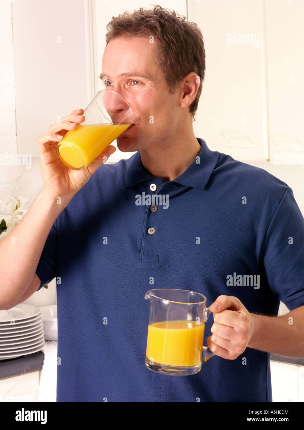 MAN IN KITCHEN DRINKING ORANGE JUICE Stock Photo - Alamy