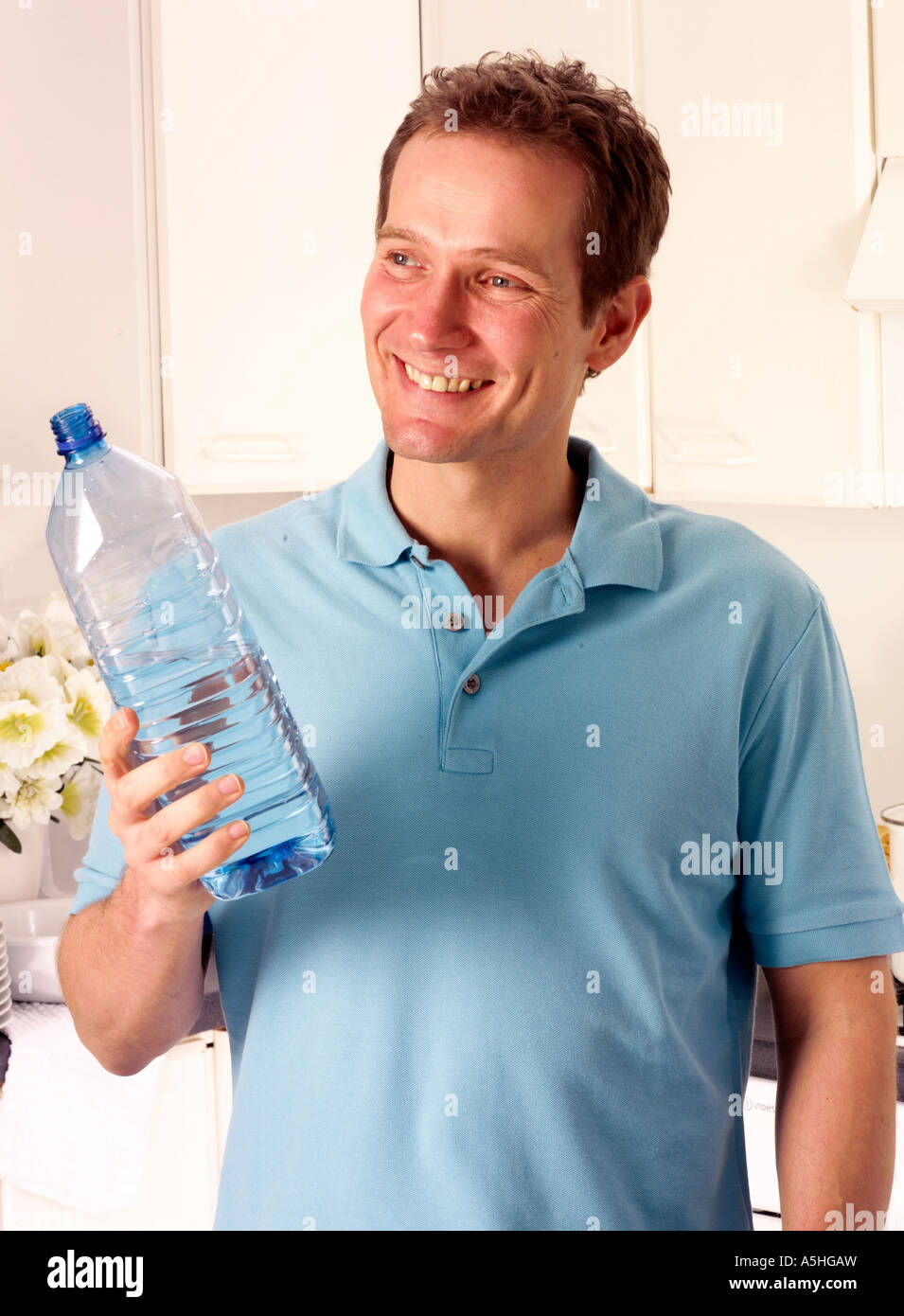 MAN IN KITCHEN HOLDING BOTTLE OF WATER Stock Photo - Alamy