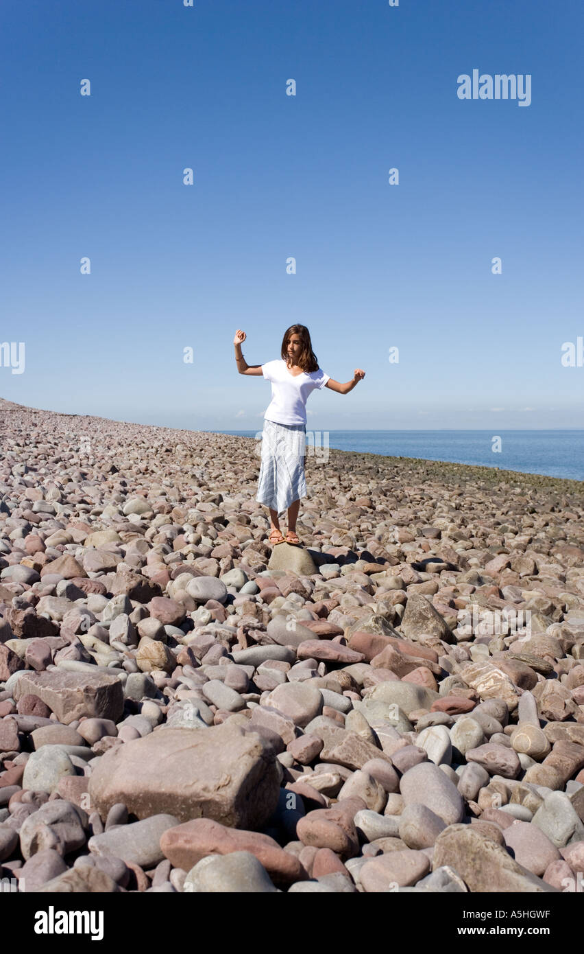 Teenage Girl Balancing on Boulder on Pebble Beach Stock Photo - Alamy