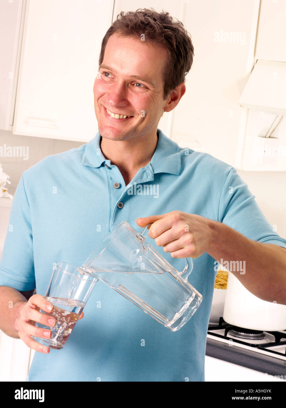 MAN IN KITCHEN POURING GLASS OF WATER Stock Photo - Alamy