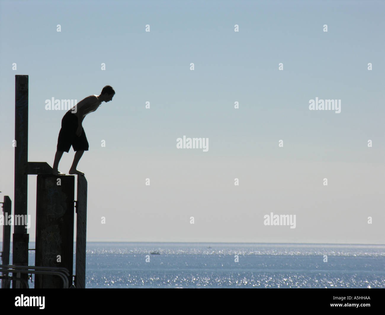Boy standing on pier looking down before jump into sea Stock Photo - Alamy