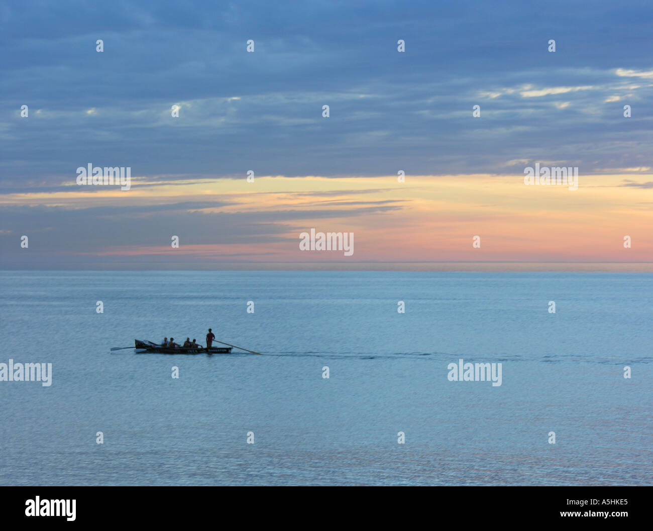 Men rowing in surfboat on sea after sunset helmsman standing Stock ...
