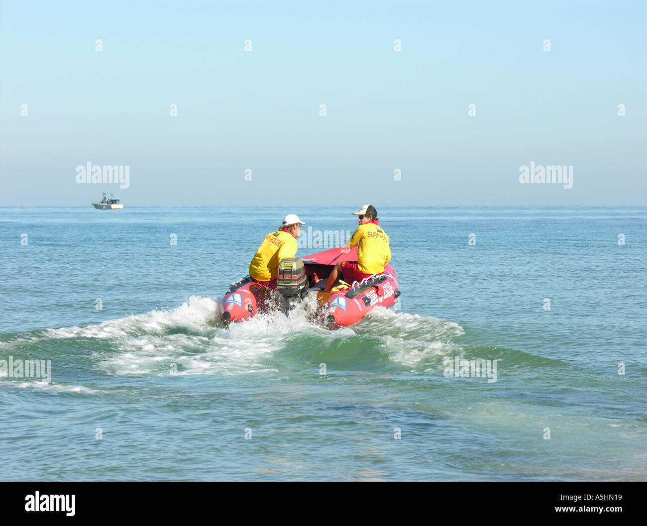 Surf rescue lifesavers riding outboard rubber boat into sea Stock Photo ...