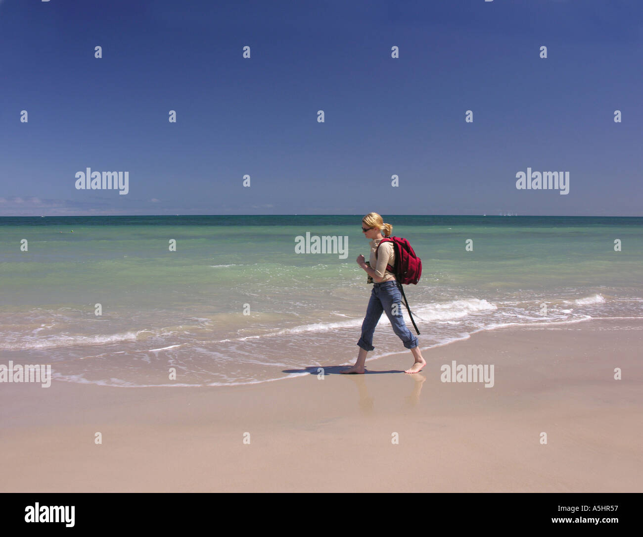 Young female backpacker walking on beach Stock Photo - Alamy