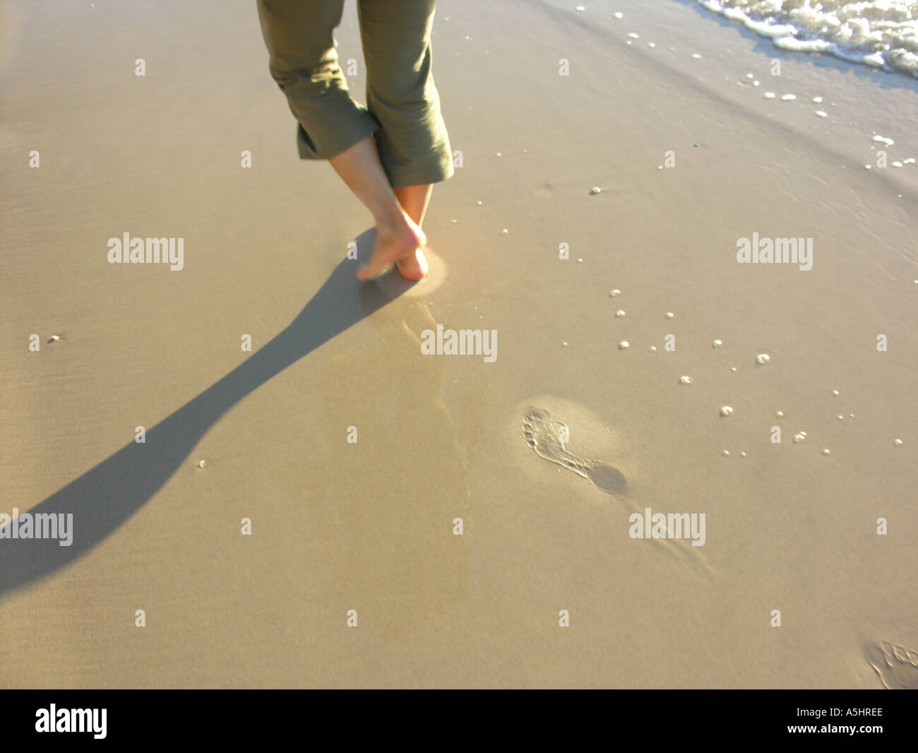 Young woman's legs throwing shadow, footprints in wet sand Stock Photo ...