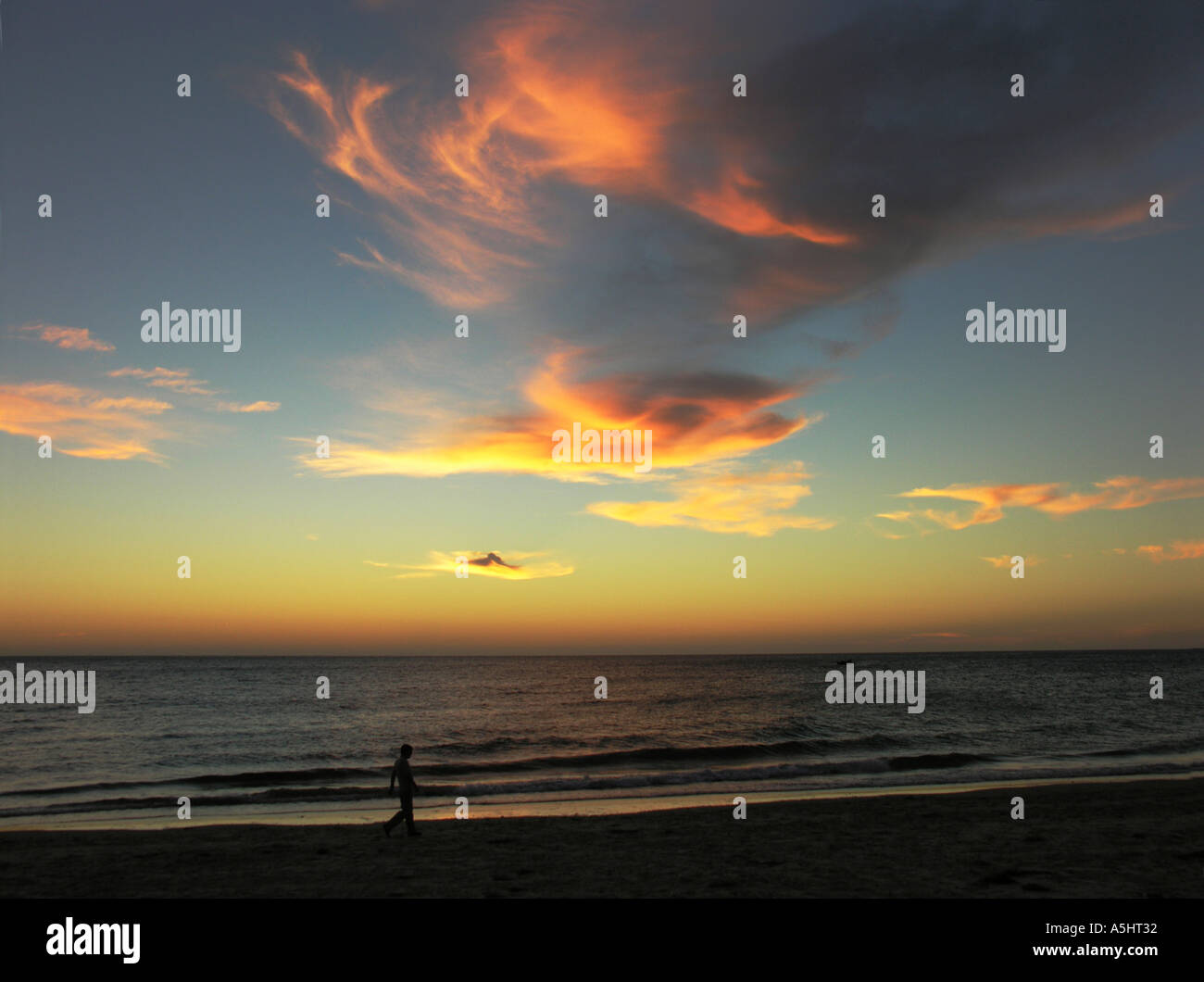 Man walking on beach at spectacular sunset afterglow clouds Stock Photo ...