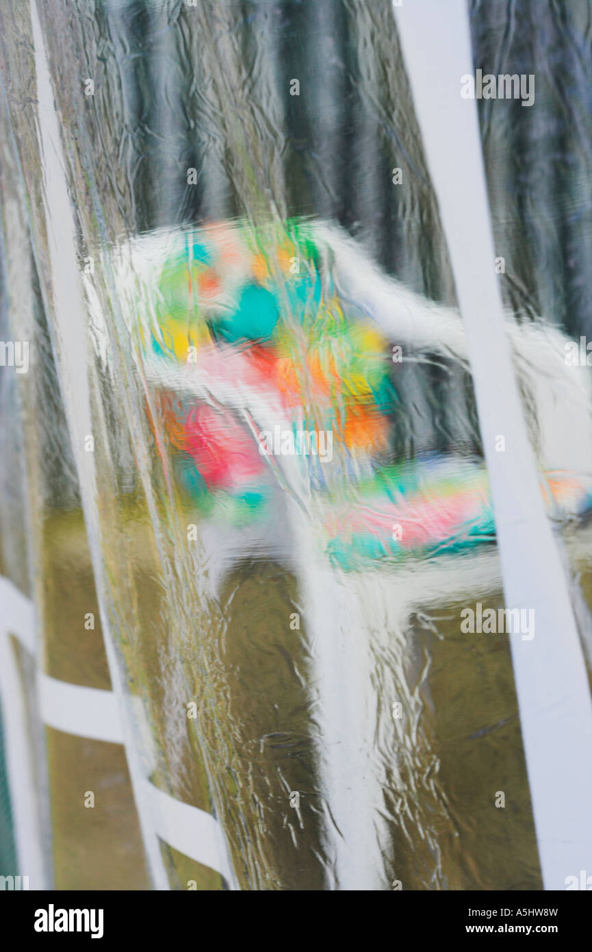 white plastic garden chair on a patio distorted through a plastic ...