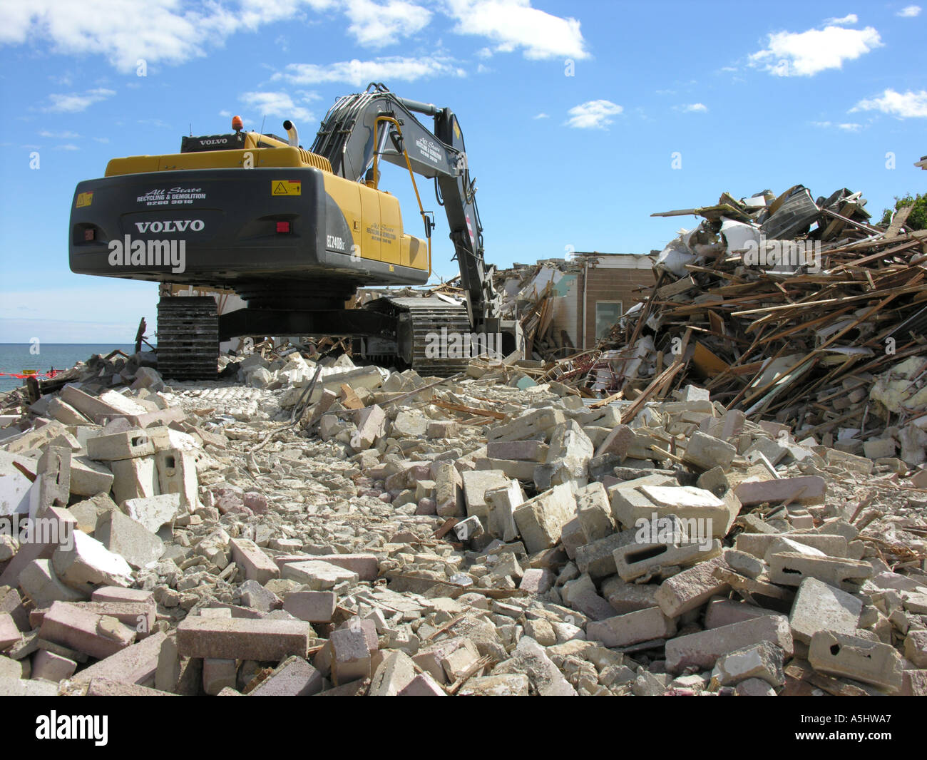 Excavator with rubble of demolished building Stock Photo - Alamy