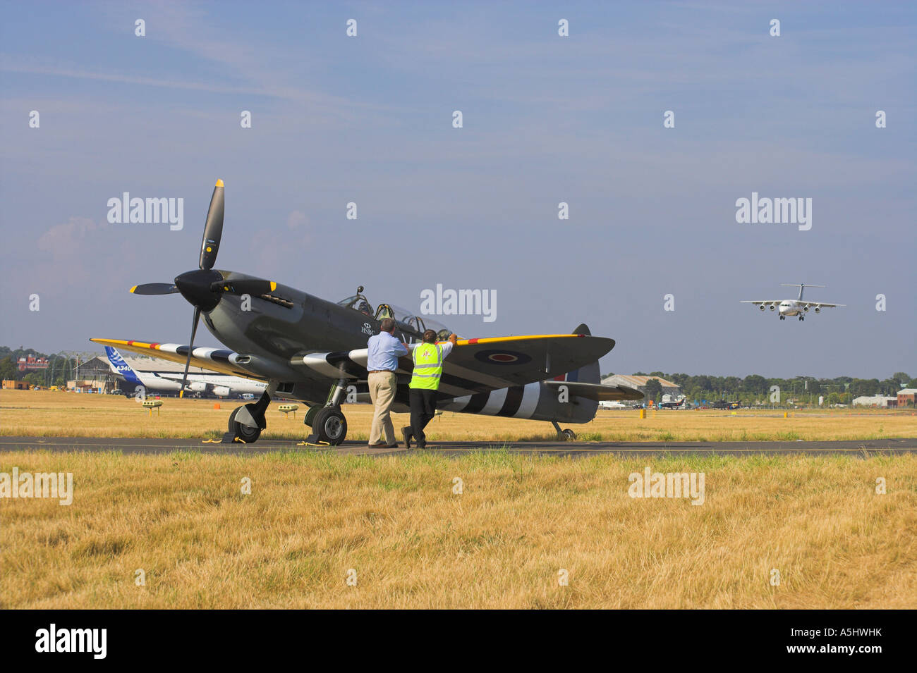 Spitfire waits its turn to take off with ground crew standing by and ...
