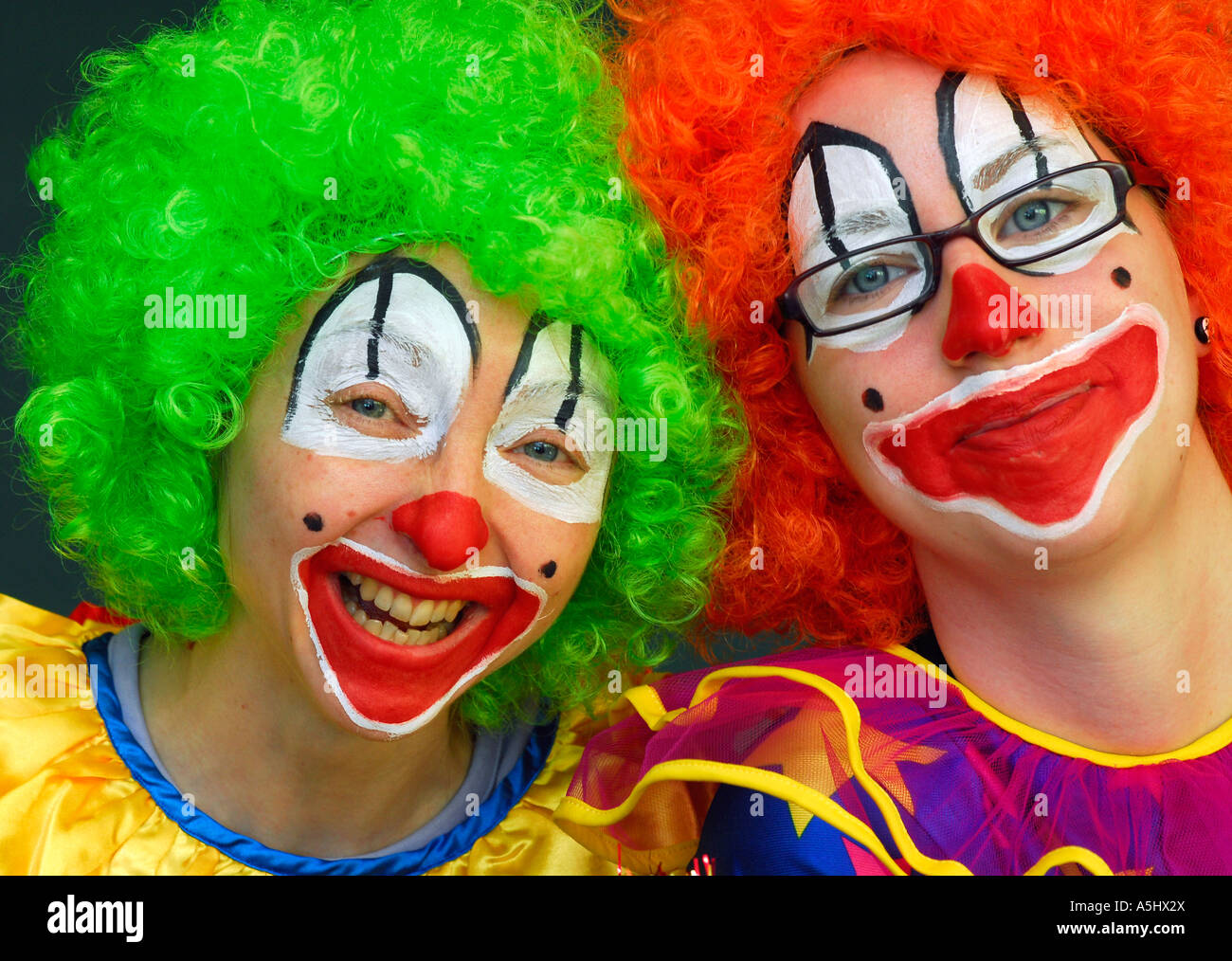 Two young women dressed as clowns in preparation for summer carnival ...