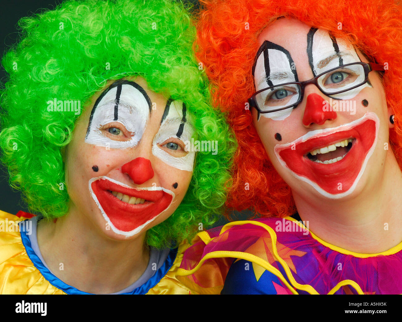Two young women dressed as clowns in preparation for summer carnival ...