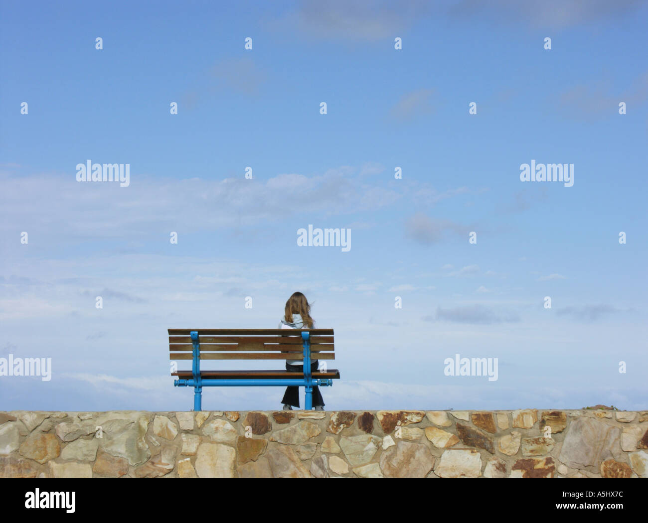 Young girl sitting on bench watching clouds Stock Photo - Alamy